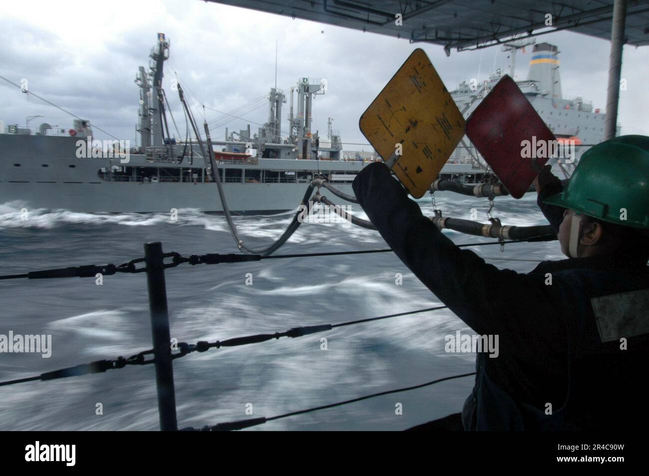 US Navy Seaman of deck department signals to the Underway Replenishment ...