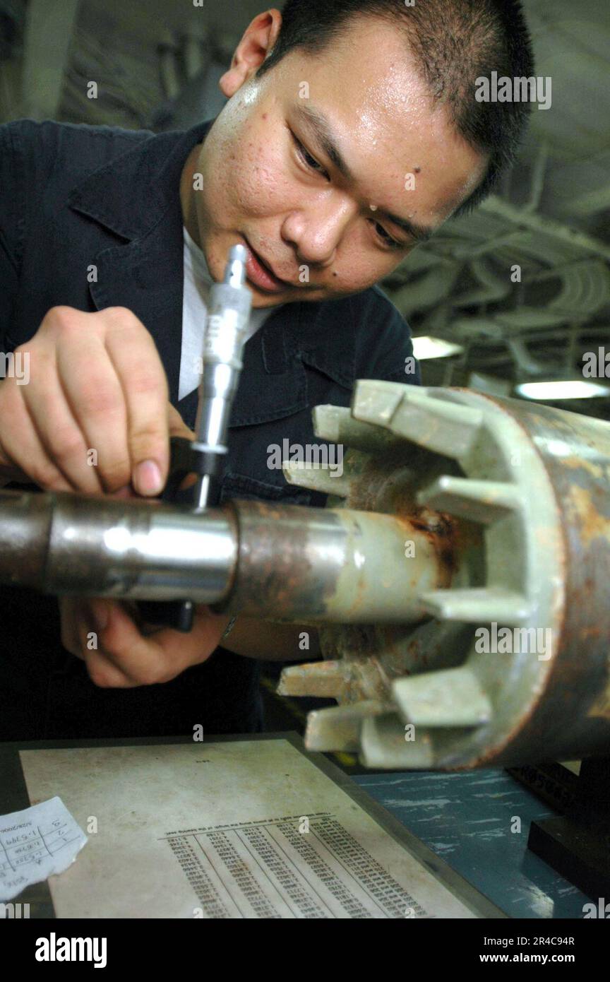 US Navy Machinery Repairman Fireman uses a caliper to measure a bearing ...