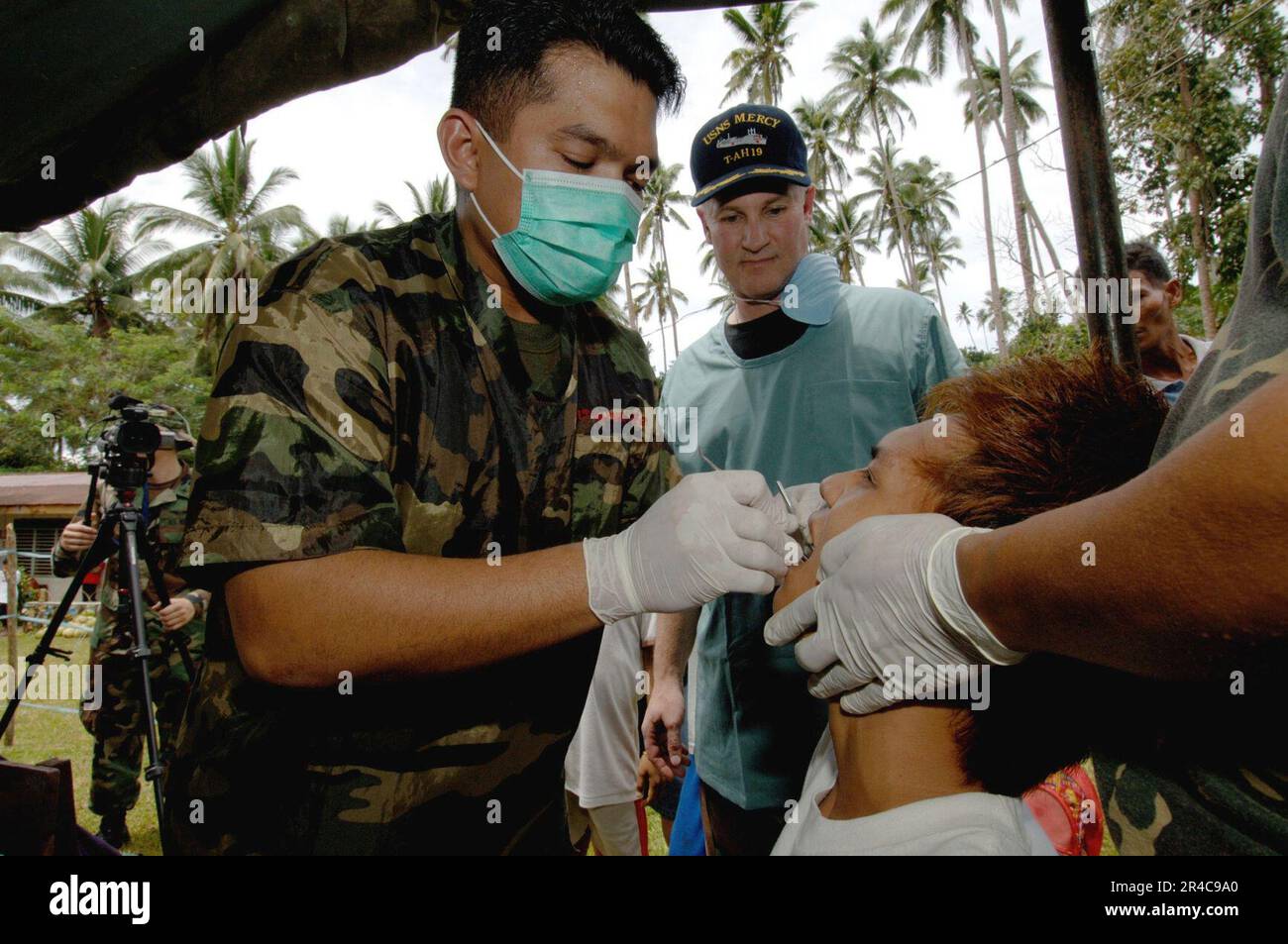 US Navy Col. observes the technique used by a Filipino dentist to ...