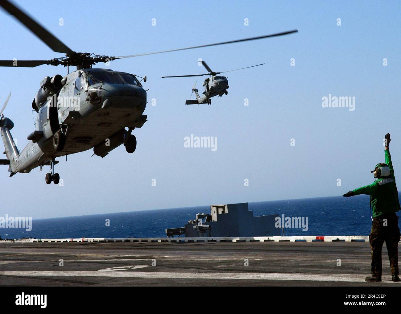 US Navy Aviation Structural Mechanic 3rd Class directs an SH-60F Seahawk assigned to the ...