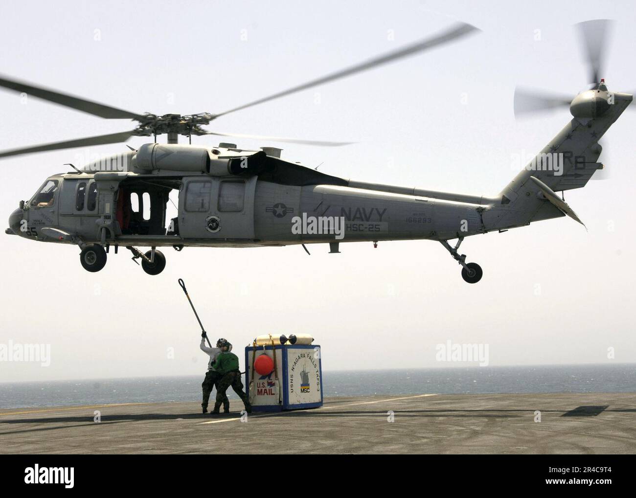 US Navy Supply Department personnel attach a cargo pendant to an MH-60S ...