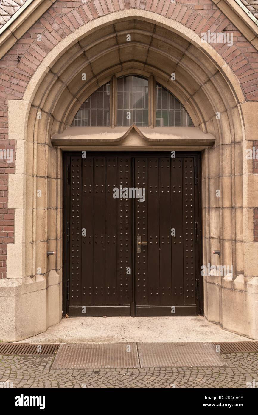 A vertical shot of two wooden doors side by side on a brick building ...