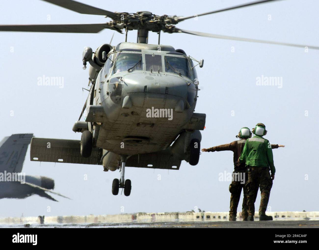 US Navy Sailors direct an SH-60F Seahawk helicopter, assigned to the Dragonslayers of Helicopter ...