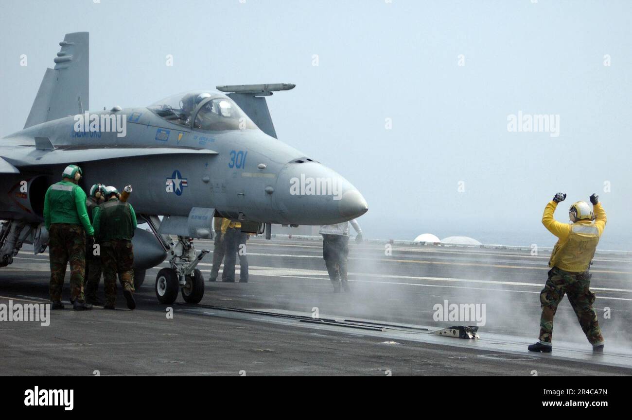 US Navy An Aviation Boatswain Mate Handler guides a F-A-18C Hornet to ...