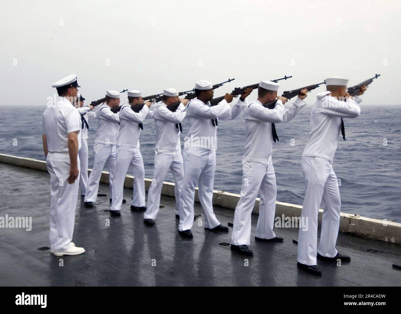 US Navy A firing squad fires three rounds during a burial-at-sea ...