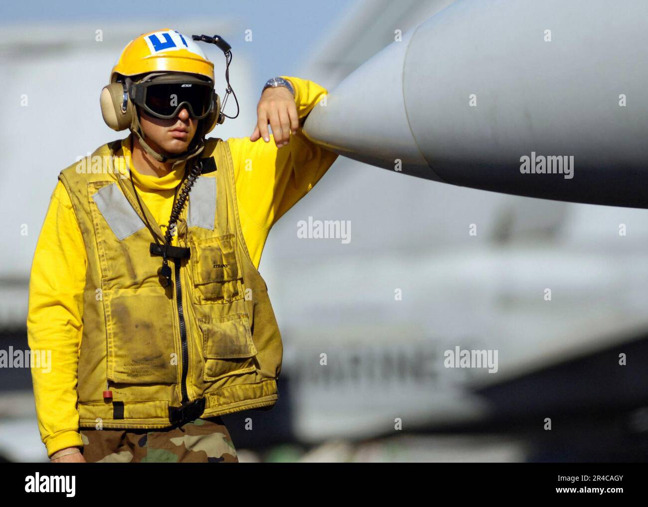 US Navy Aviation Boatswain's Mate 3rd Class leans against the nose of ...