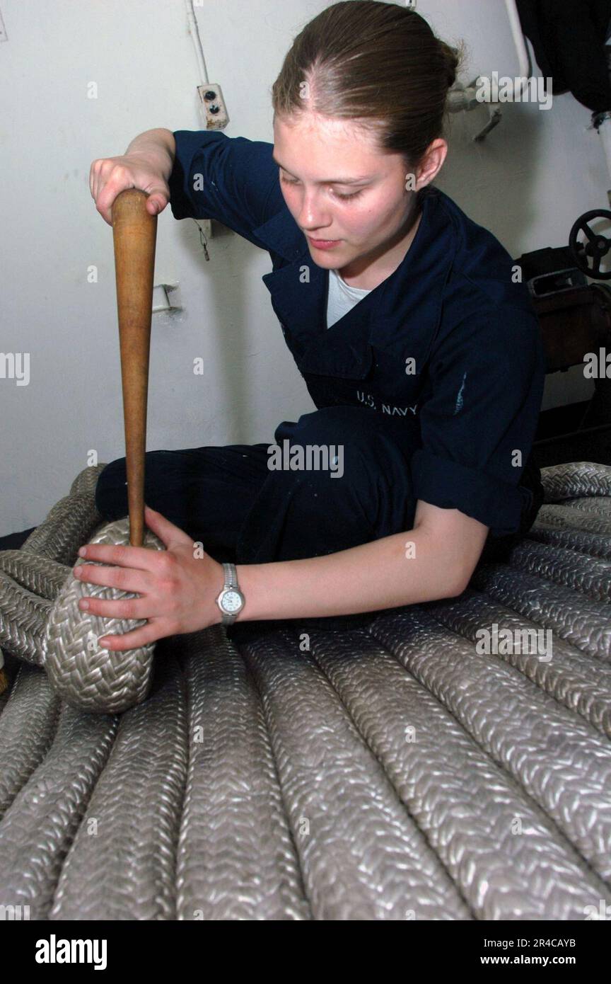 US Navy Seaman uses a fid to repair a snag on a mooring line aboard ...
