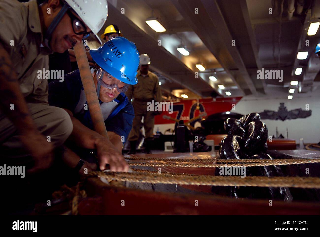 US Navy Seaman washes down an anchor chain from the foc'sle aboard the ...