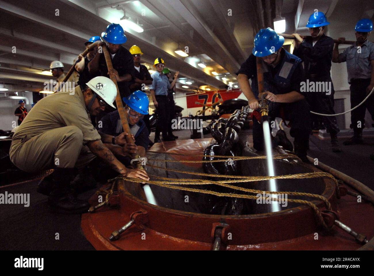 US Navy Deck Department personnel washes down an anchor chain from the ...