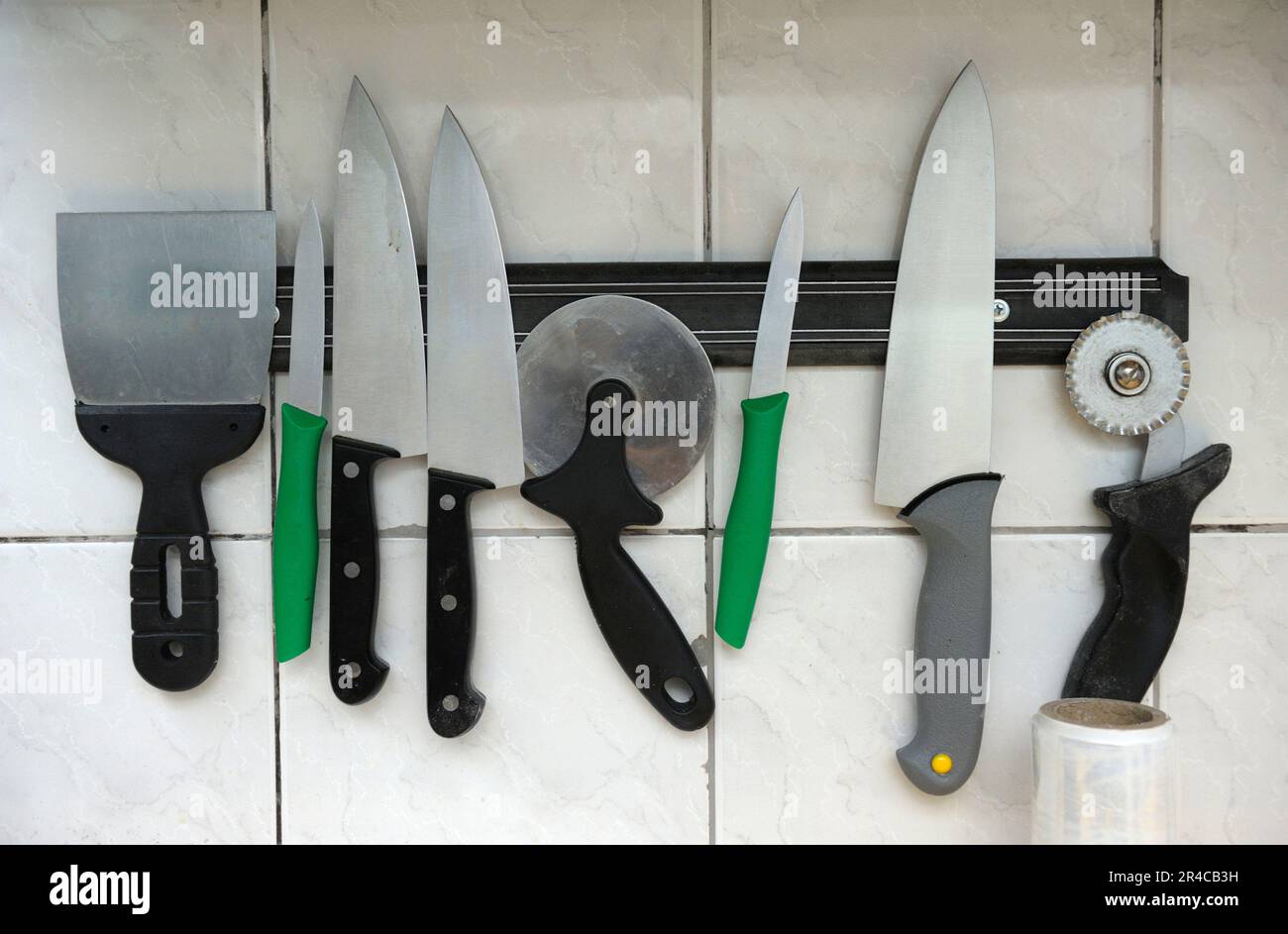 Chief's knives and other tools hanging on magnetic rack in a kitchen of ...