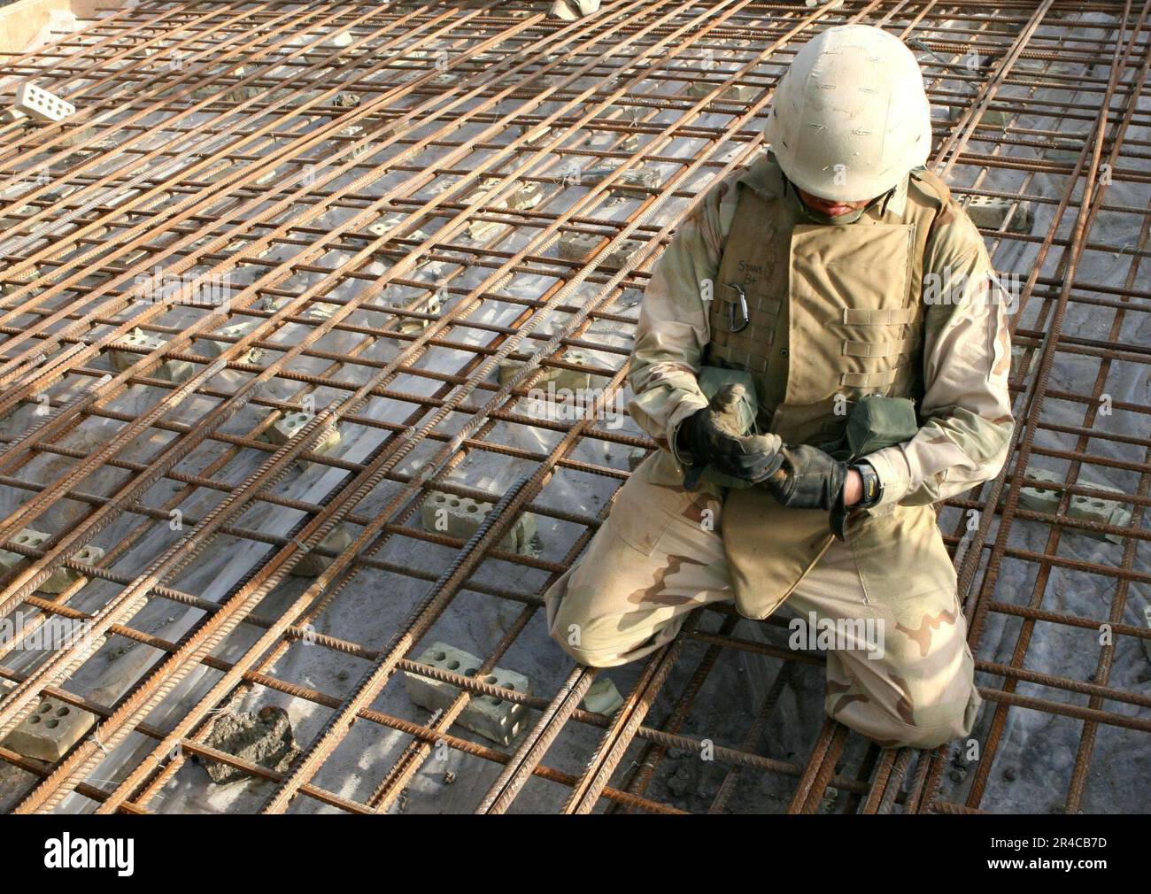 US Navy Steelworker 3rd Class ties together rebar before a concrete ...