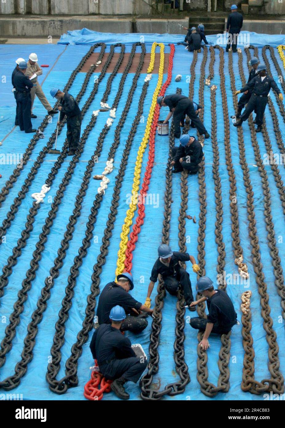 US Navy Boatswain's Mates paint the anchor chains aboard the guided ...