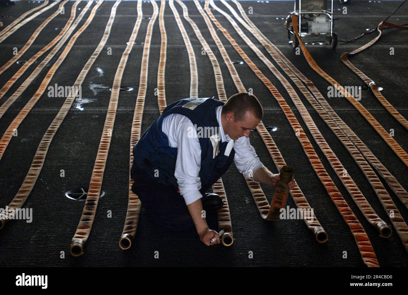 US Navy Aviation Boatswain's Mate Airman inspects fire hoses prior to ...
