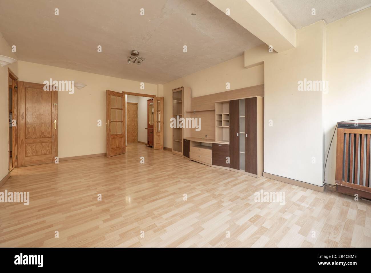 A spacious half-empty living room with a wooden floor and pine wood ...