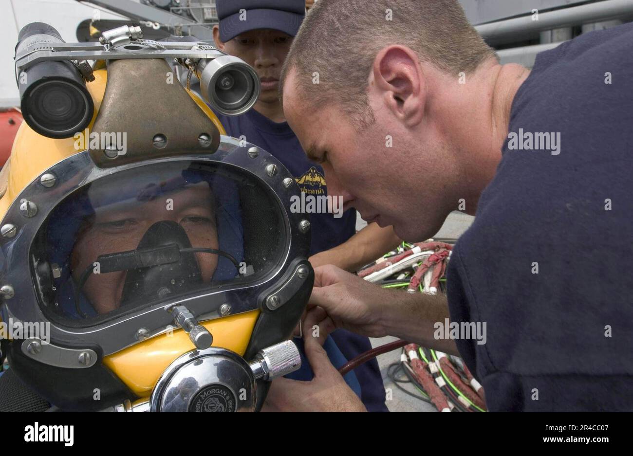 US Navy Royal Thai Navy diver Ensign has a MK-21 diving helmet fastened ...