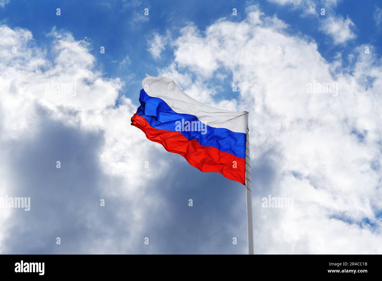 Russian white-blue-red flag is waving in front of blue sky and clouds ...