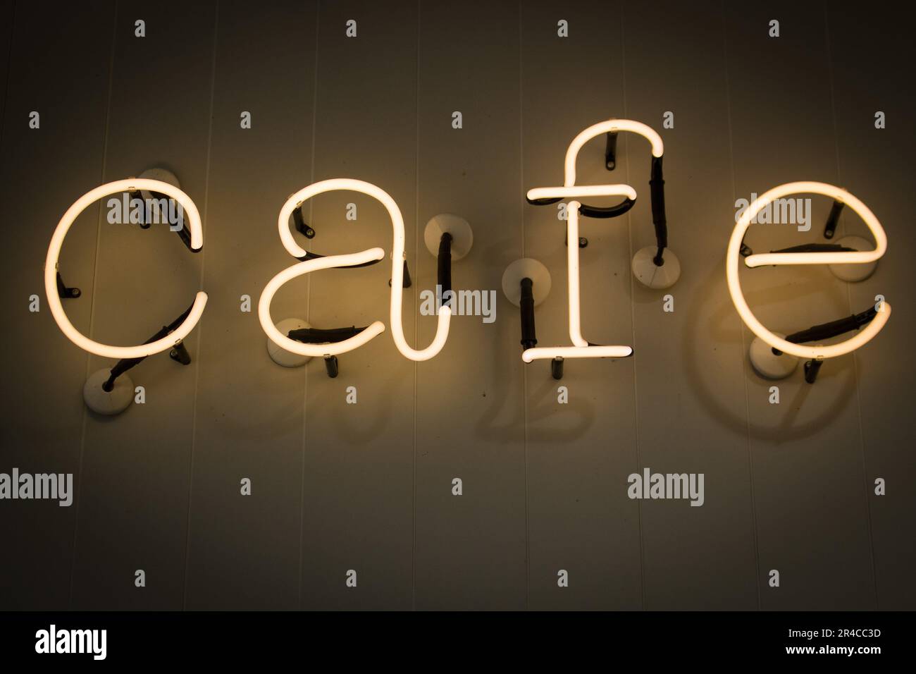 A black and white neon sign for a cafe, illuminated against a dark ...