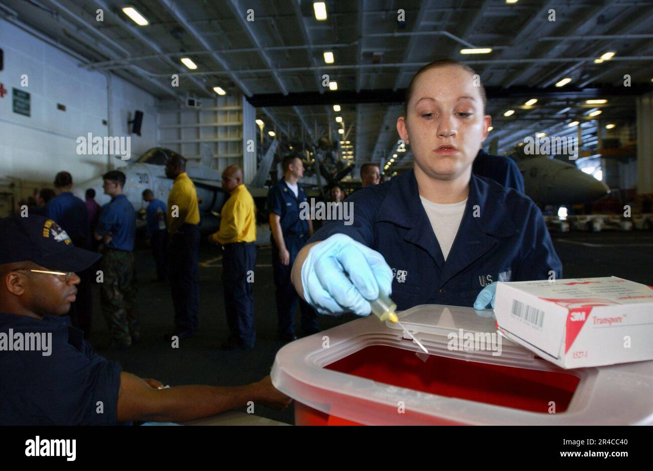 US Navy Airman drops a needle into a sharps container after taking ...