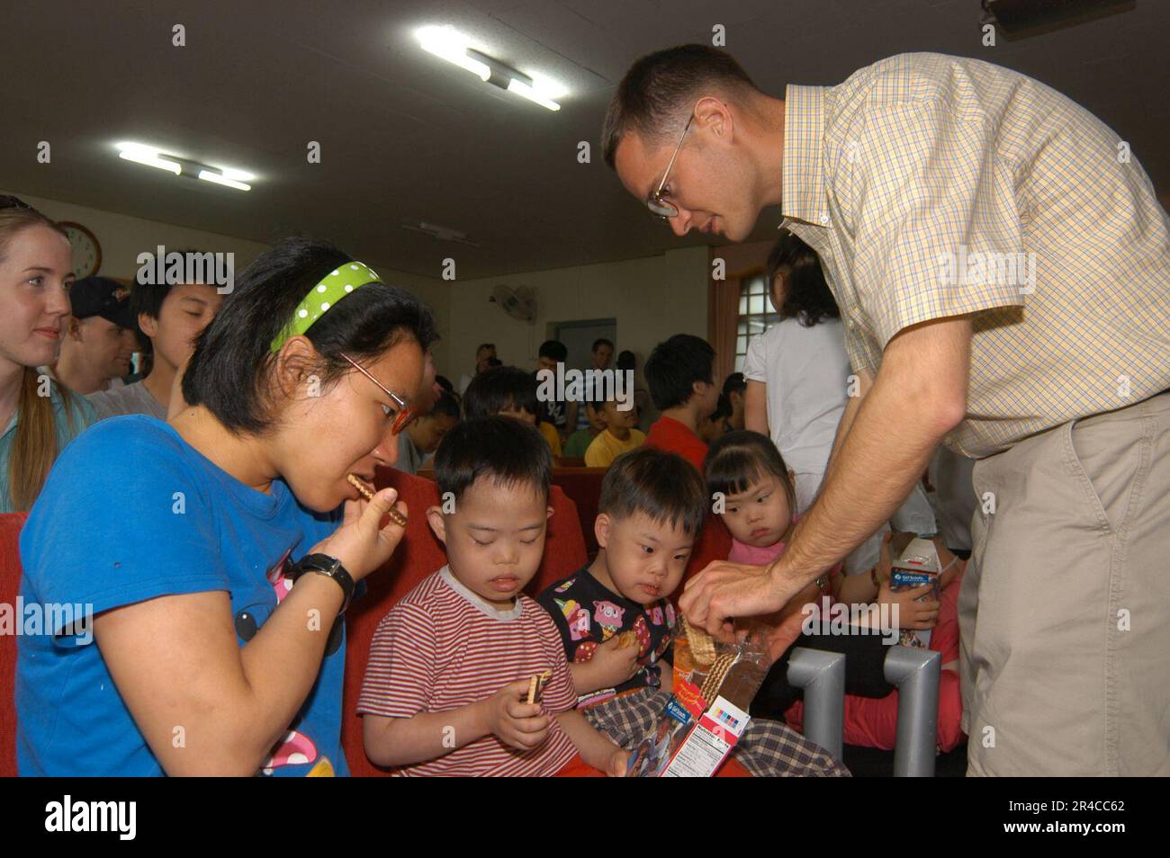 US Navy Seaman hands out cookies to children at the Jinhae Jae-Hual-Won ...