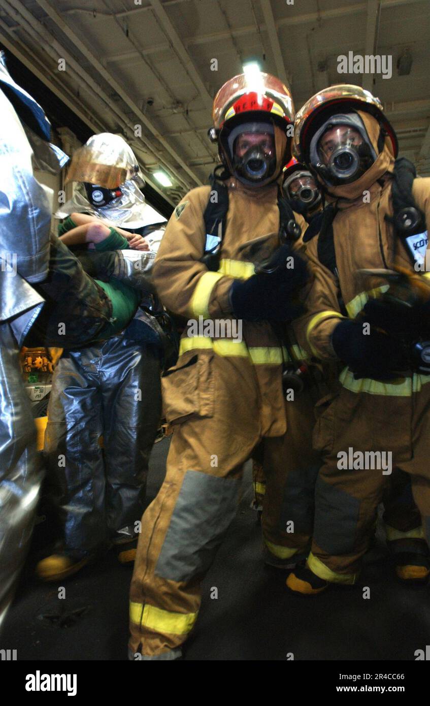 US Navy Sailors working on a fire fighting team simulate putting water ...