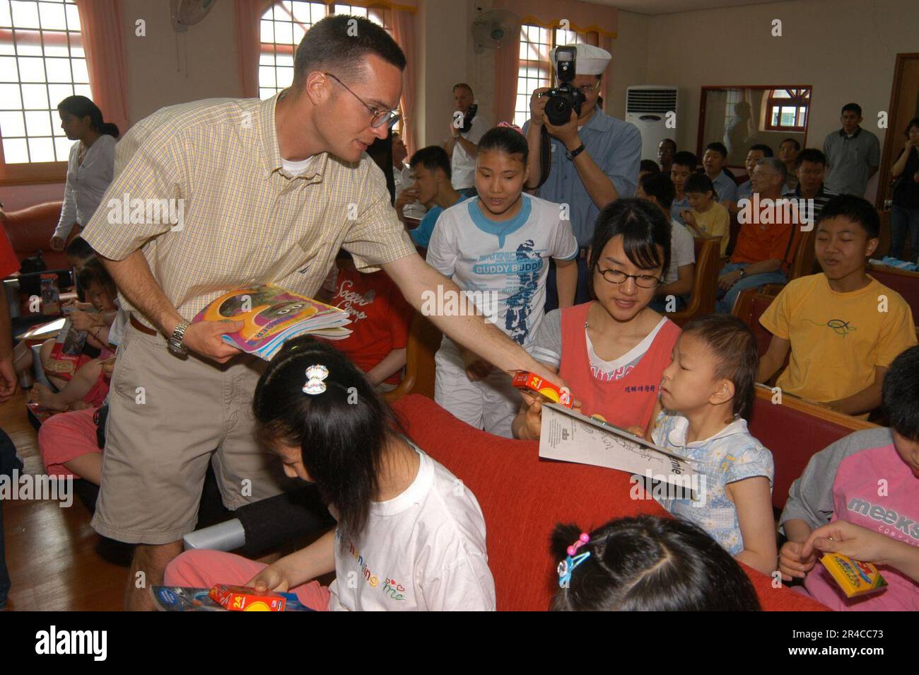 US Navy Seaman hands out coloring books to children at the Jinhae Jae ...