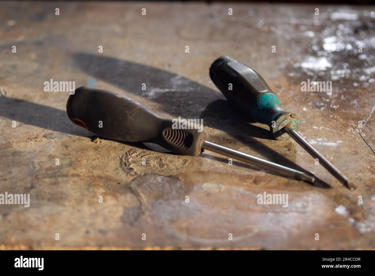 Two tools placed side-by-side on a wooden bench, illuminated by natural ...