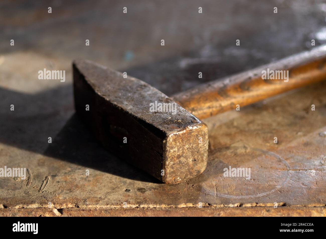 An aged metal hammer lies atop a wooden block on a hard surface Stock ...