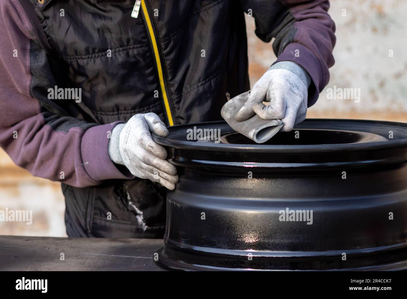 A male mechanic is diligently replacing a car tire with a new one ...