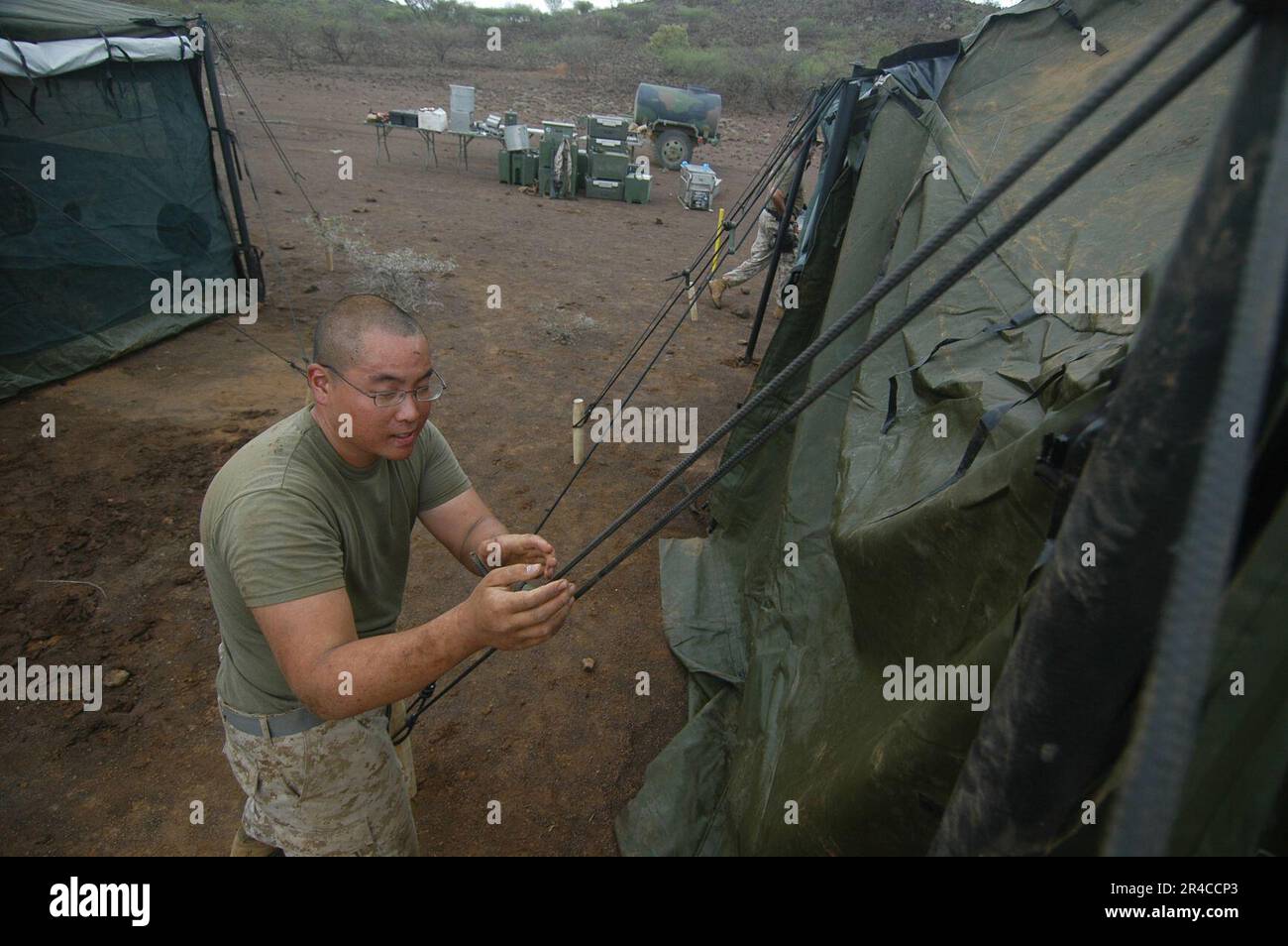 US Navy U.S. Marine Lance Cpl. tightens up a corner rope while setting ...