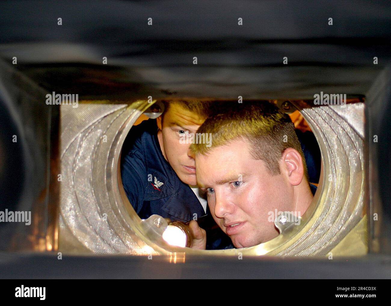 US Navy Aviation Machinist's Mate 3rd Class holds a flashlight as he ...