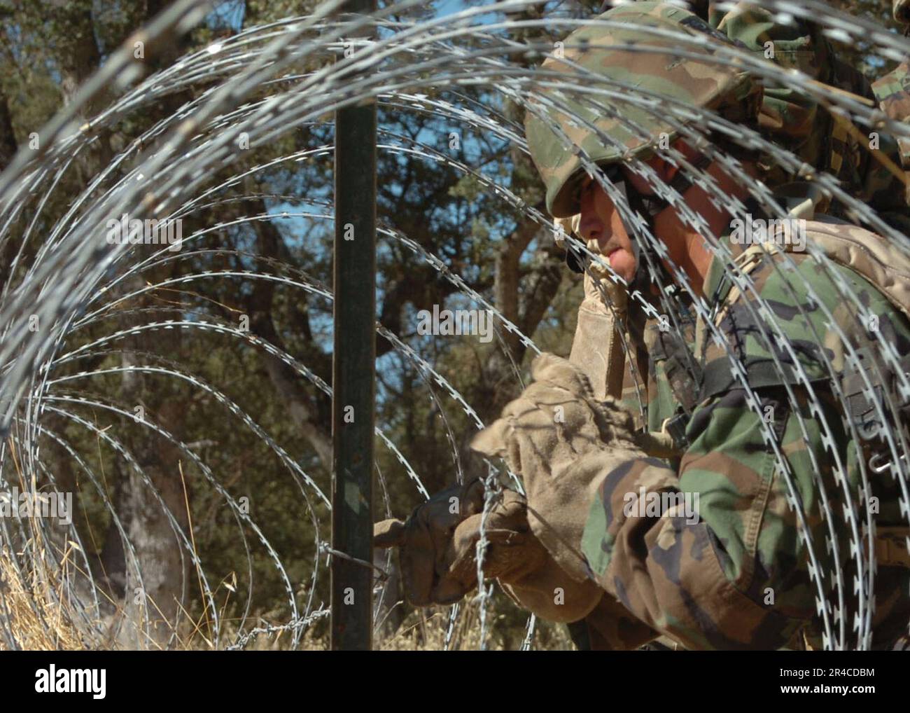 US Navy Builder Constructionmen wraps a strand of barbwire to a stake ...
