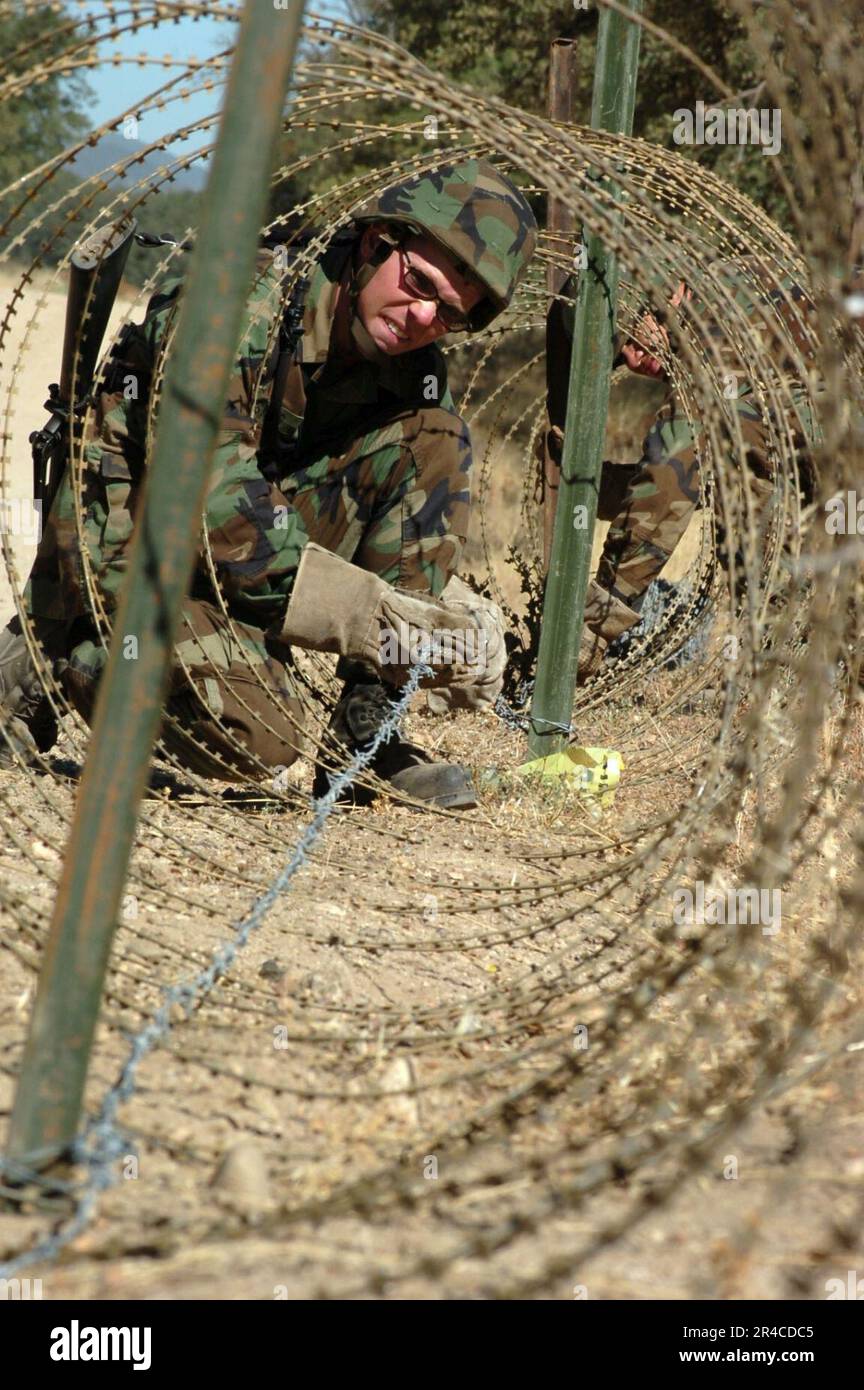 US Navy Builder Constructionmen stretches barbed wire through a spool ...