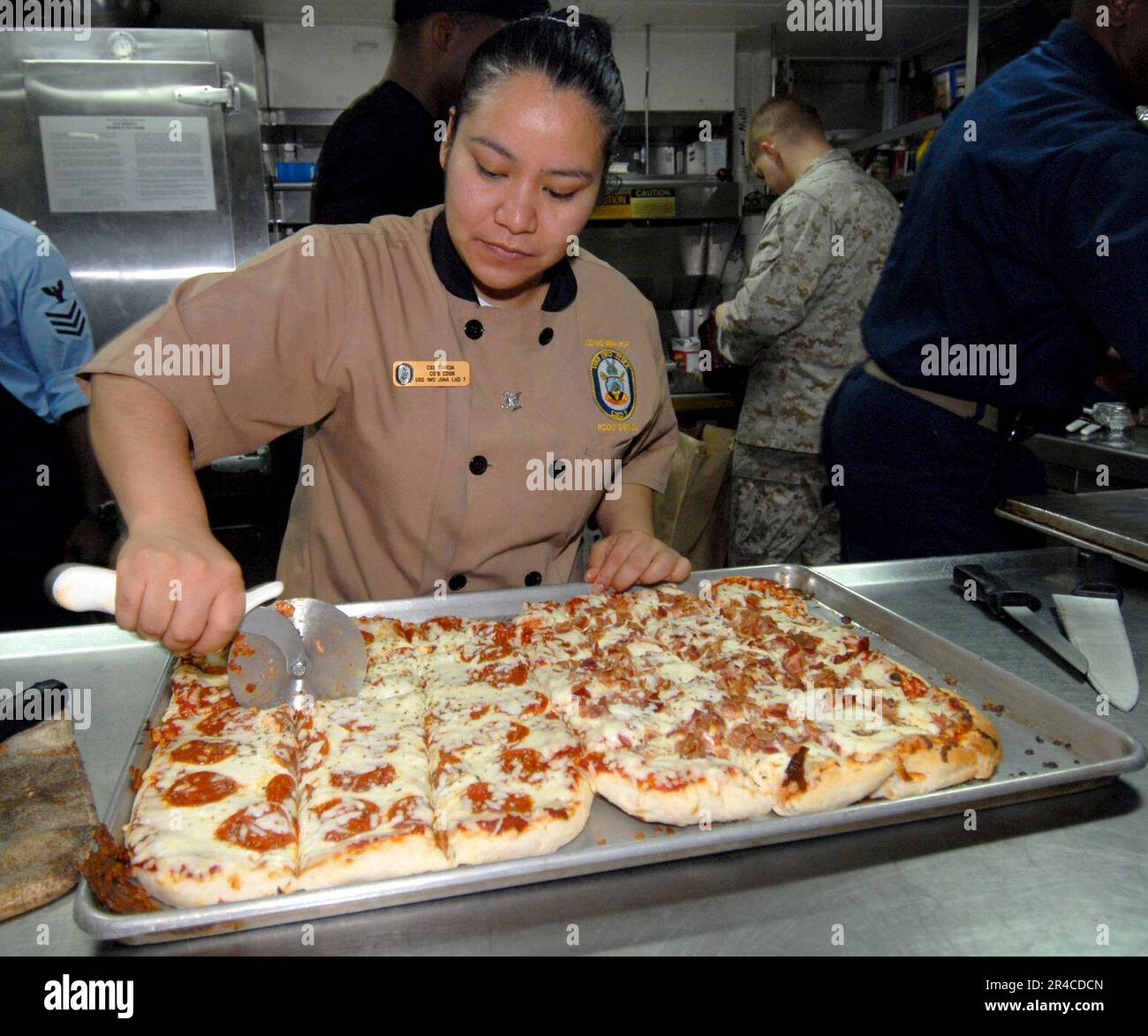 US Navy Culinary Specialist 3rd Class slices pizzas for a pizza party ...