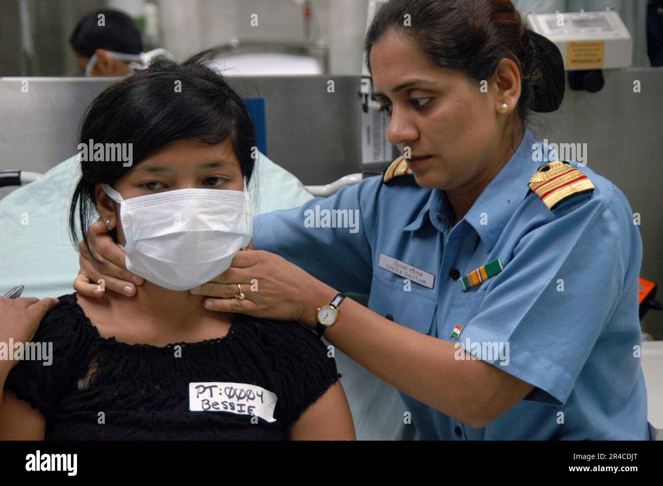 US Navy Indian Navy Cmdr. examines a patient in casualty receiving aboard the Military Sealift ...