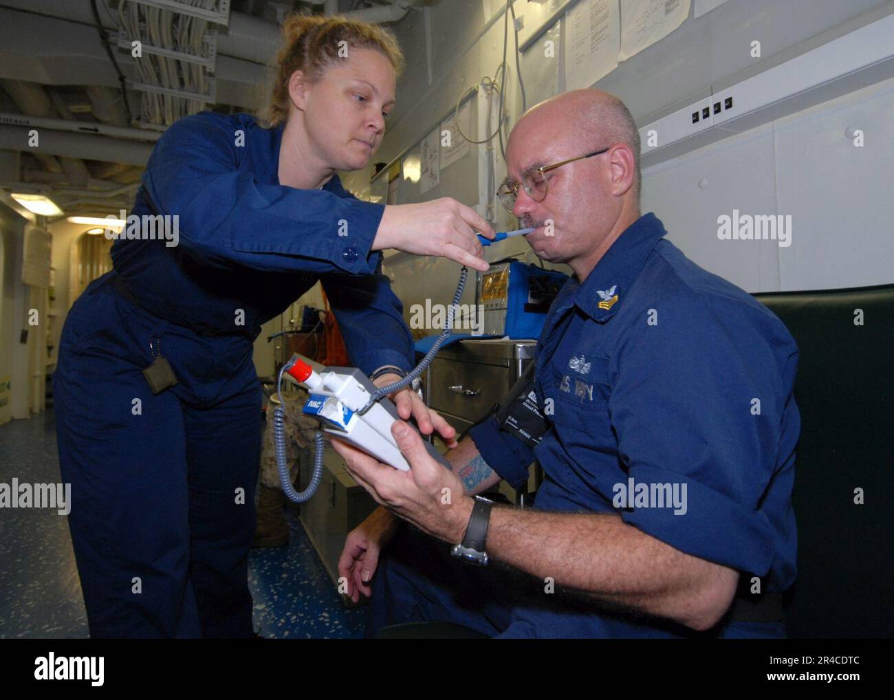 US Navy Airman takes the temperature of Sailor during sick call aboard ...