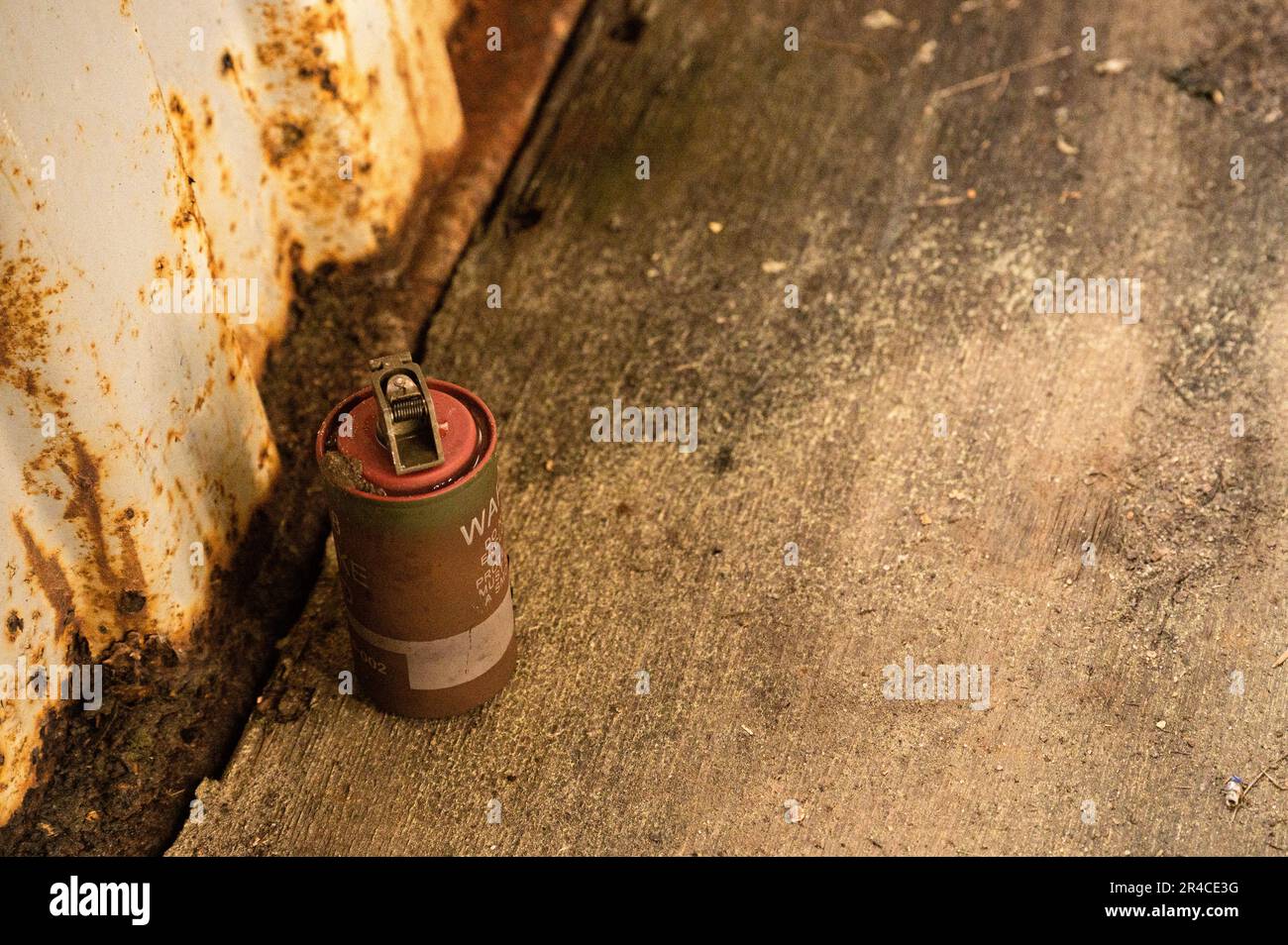 An unused smoke grenade sits in the corner of a building within a ...