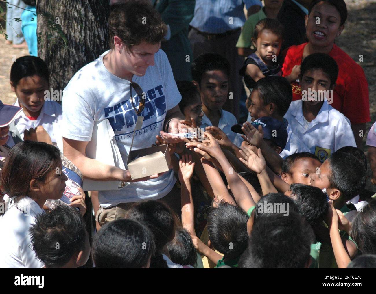 US Navy Project Hope Volunteer hands out pencils to children during a ...
