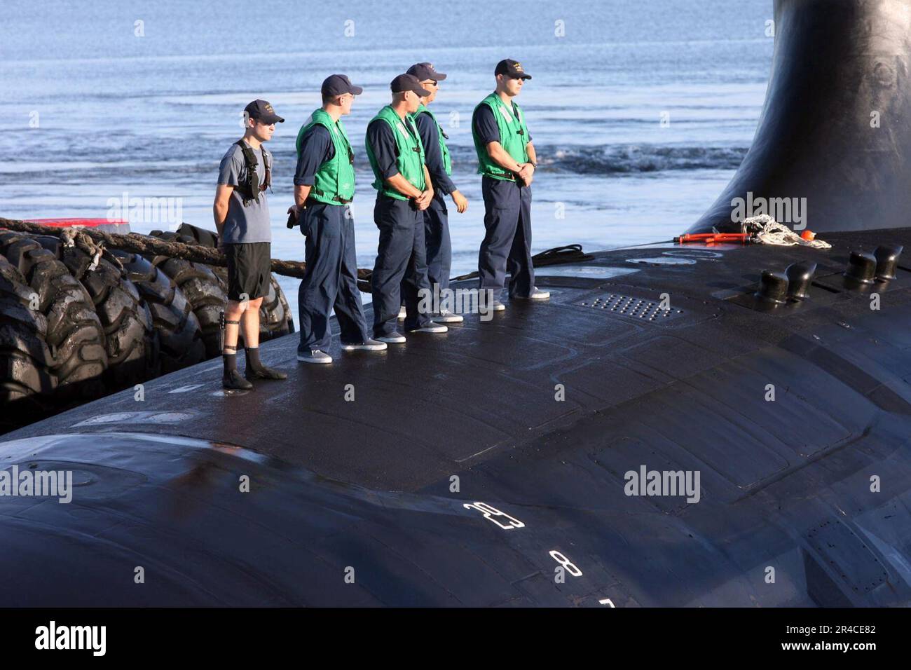 US Navy Sailors stand topside as the Virginia-class attack submarine ...