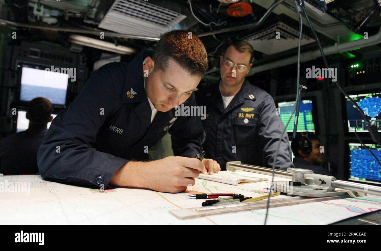 US Navy Petty 1st class left, plots a course as Lt. right, looks on in ...