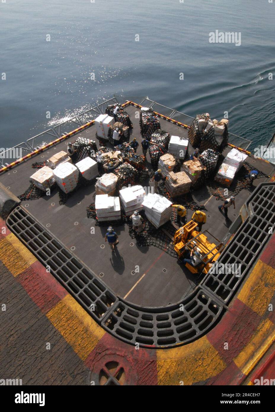 US Navy Sailors on the port side elevator move stores during a vertical ...