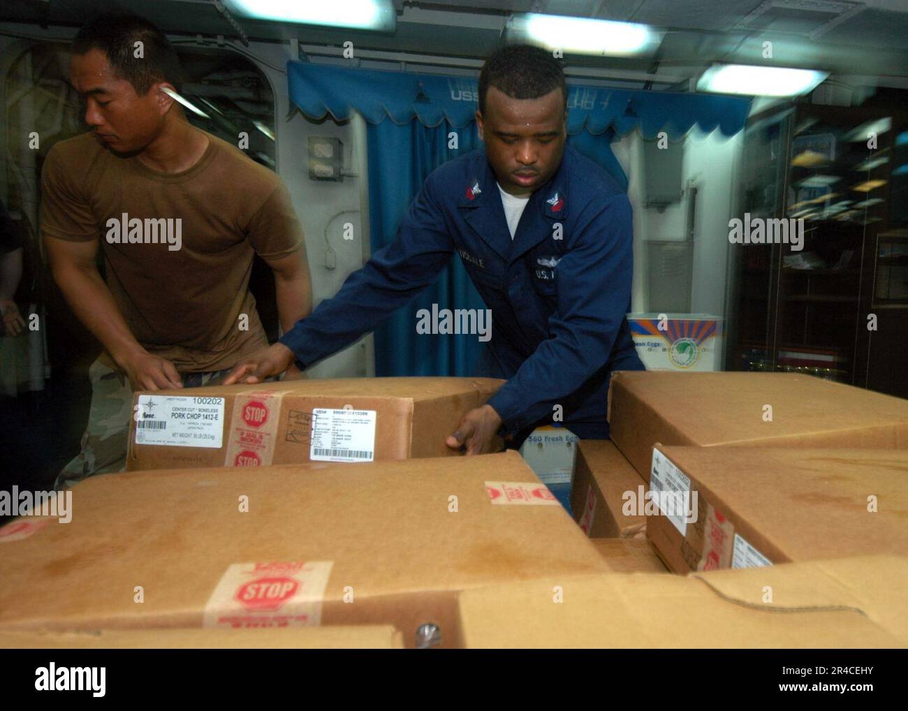 US Navy Culinary Specialist 1st Class moves boxes of frozen food to an ...