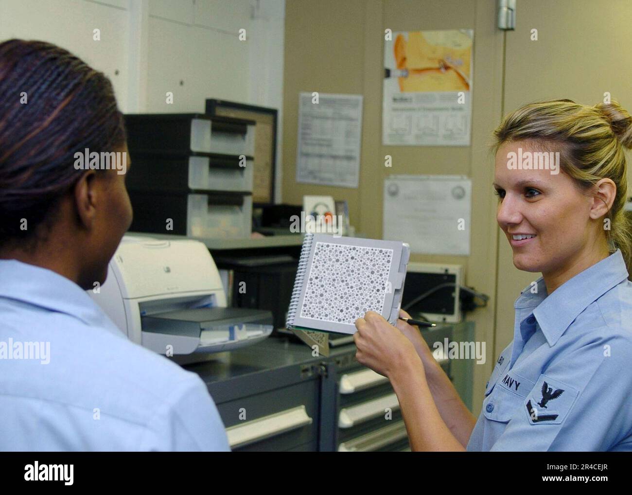 US Navy Hospital Corpsman 3rd Class performs a routine eye exam for a ...