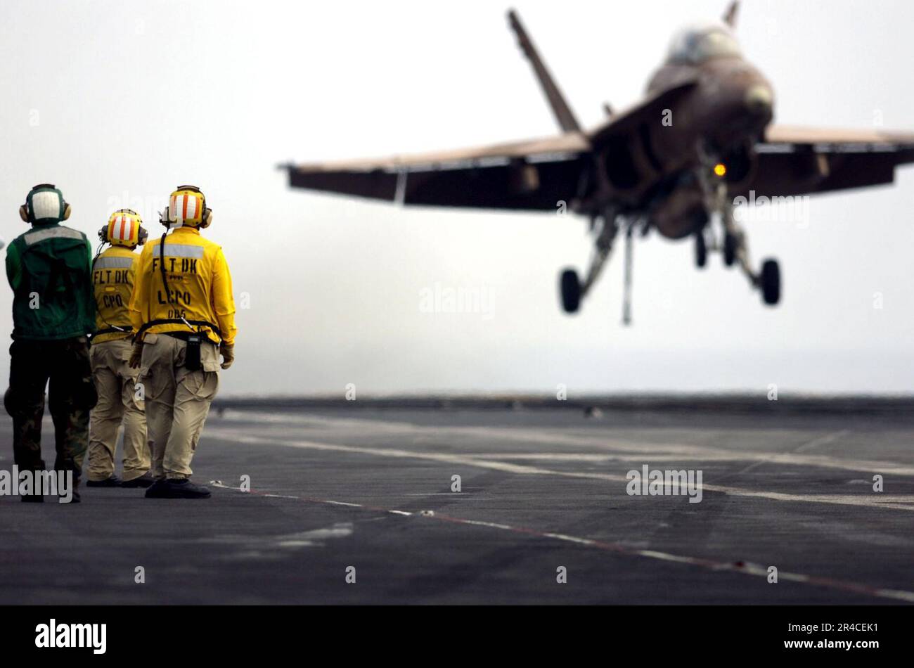US Navy Flight Deck personnel look on as an F-A-18 Hornet assigned to ...