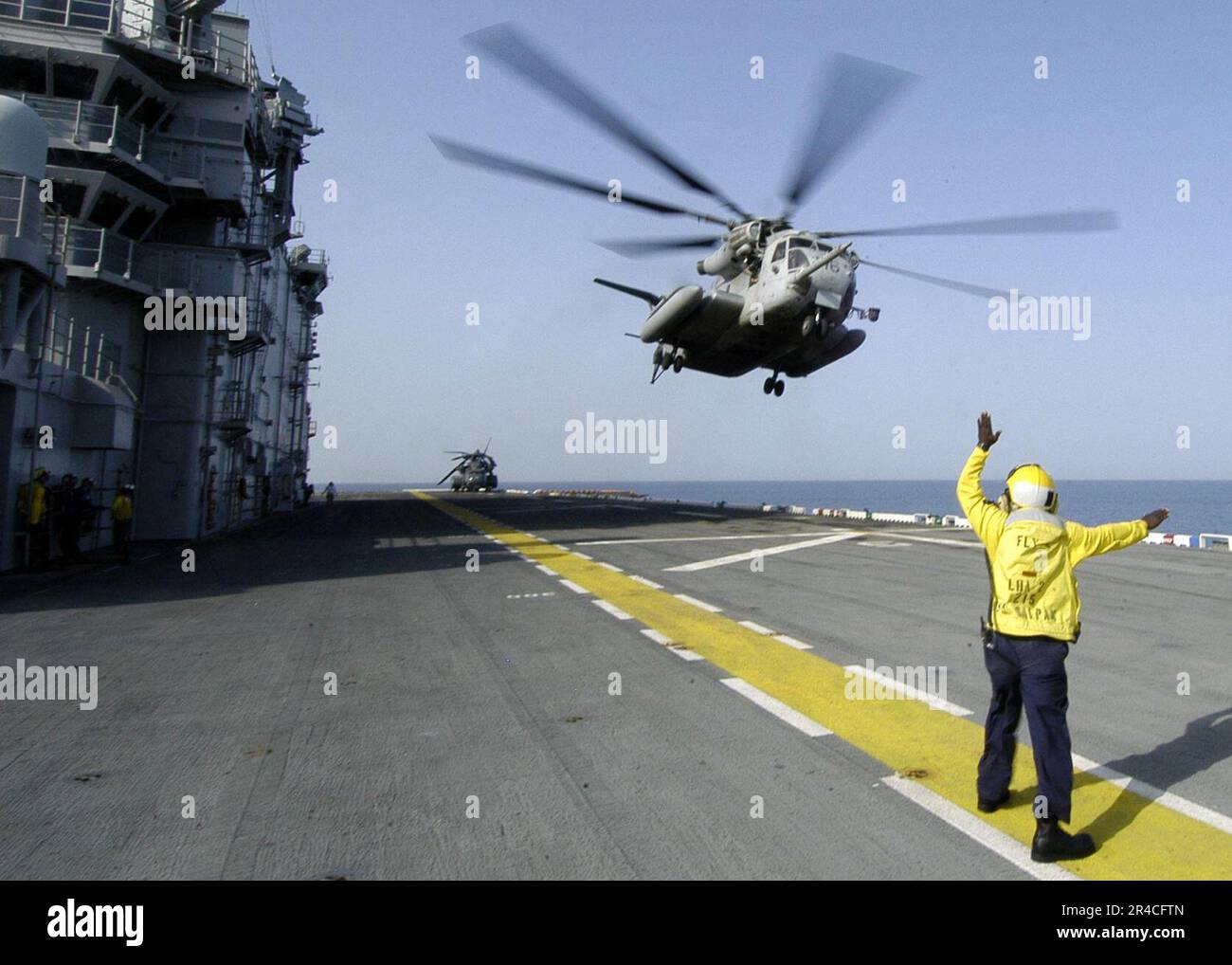 US Navy Aviation Boatswain's Mate Handler 3rd Class signals to a MH-53E ...
