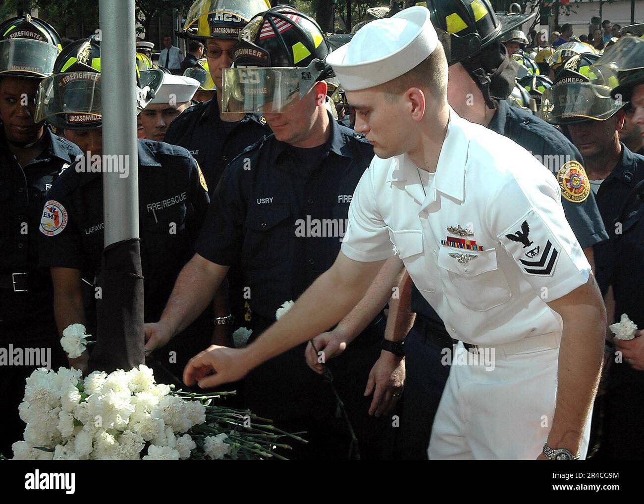 US Navy Fire Controlman 2nd Class places a carnation on the base of a 9 ...