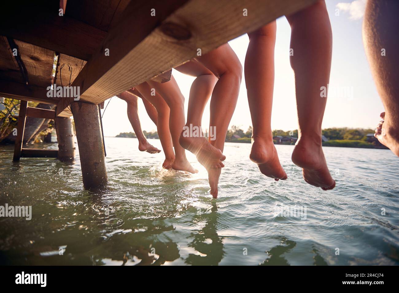 young friends sitting on the dock and enjoying together at vacation ...