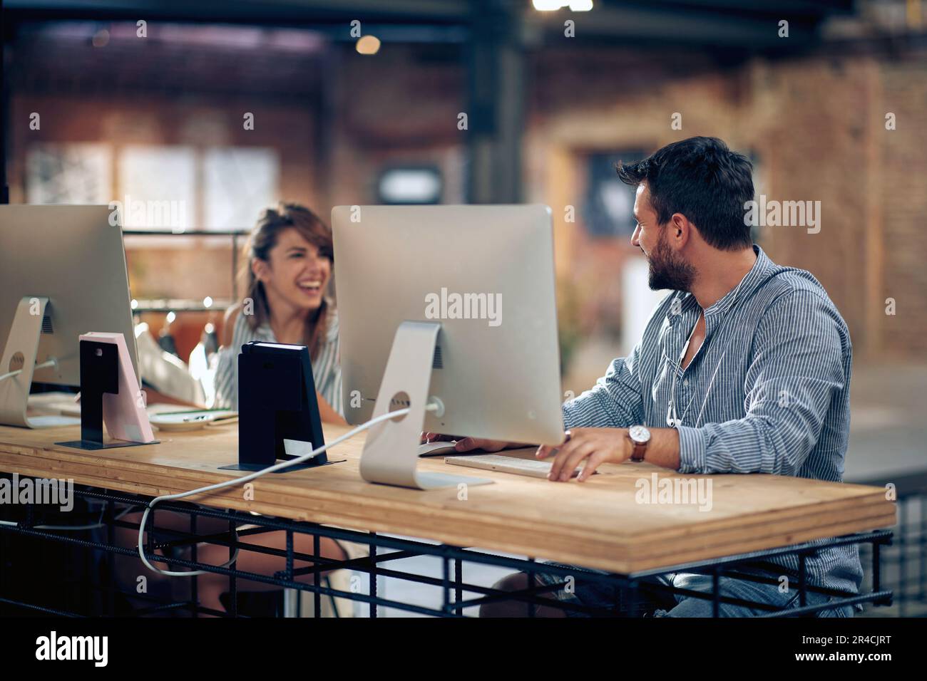 Beautiful young colleagues having fun at work, sitting in front of ...