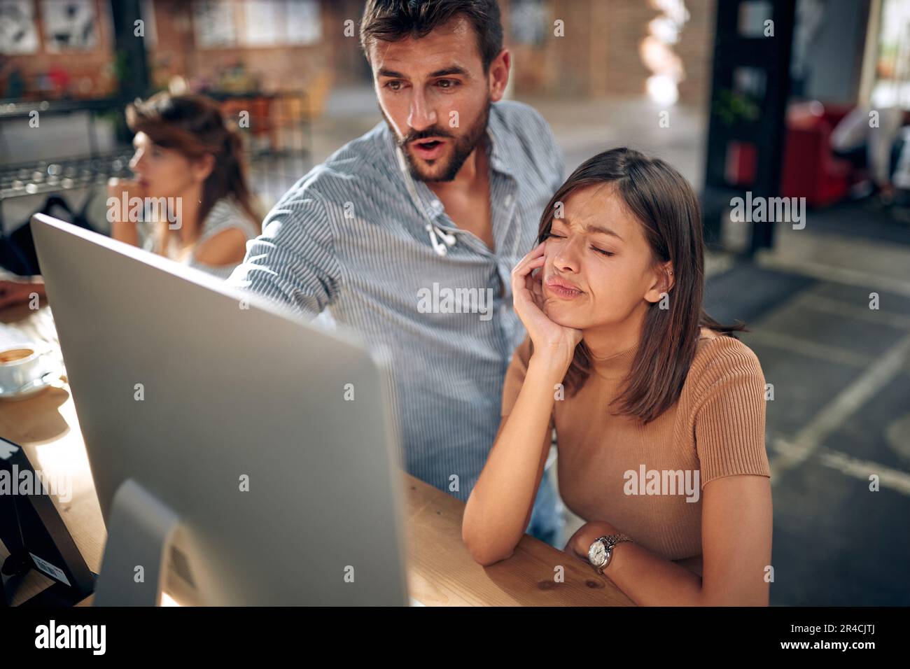 Office workers in front of computer desktops discussing project, man ...