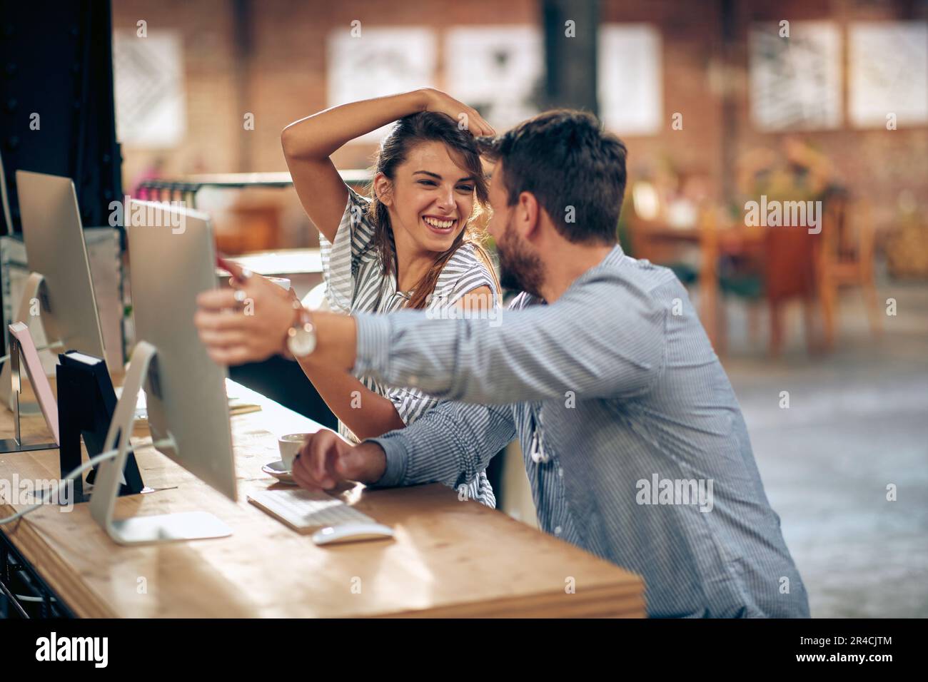 Young attractive man and woman at work chatting, sitting in front of ...