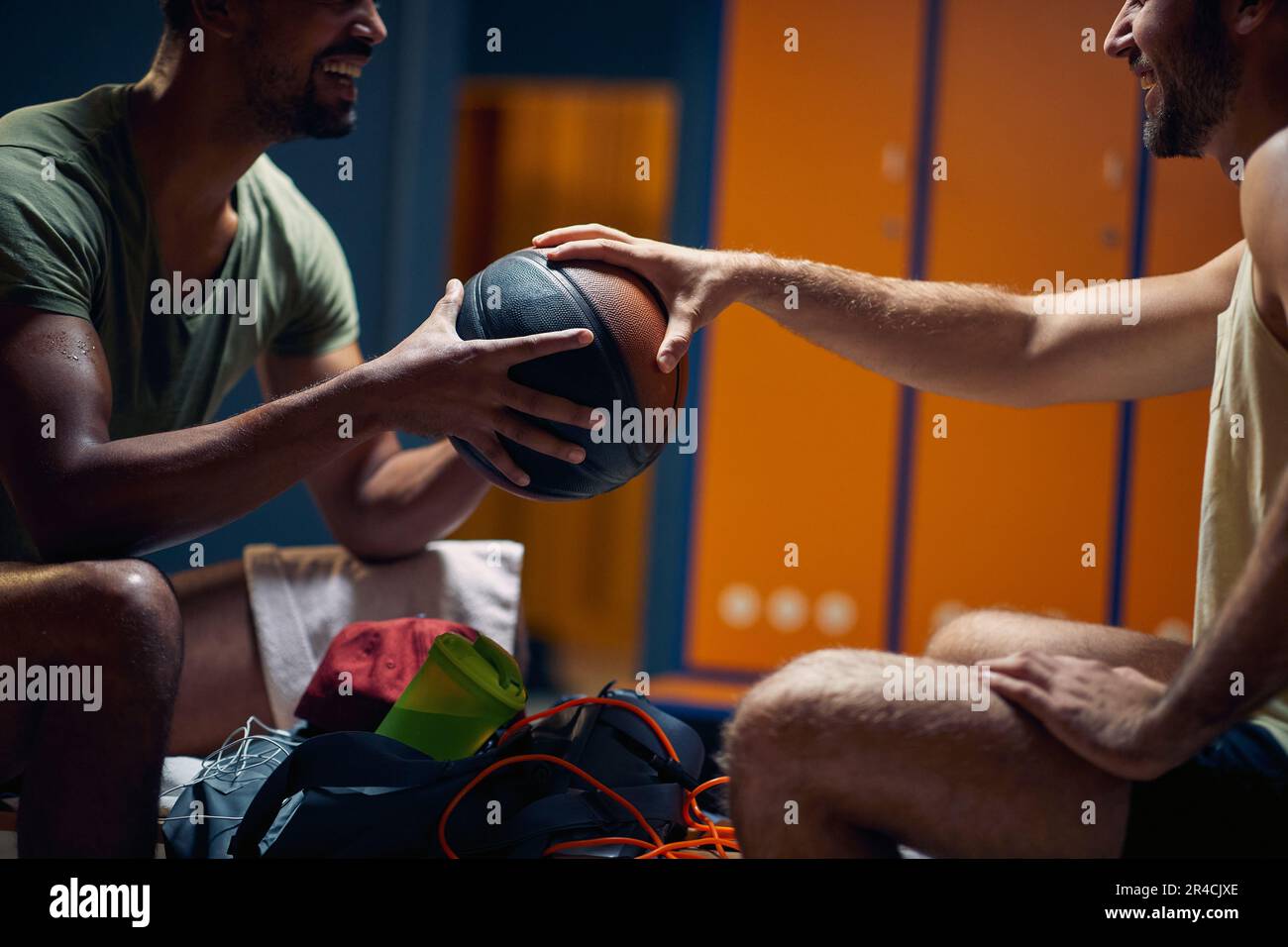 Two young players sitting face to face on bench, holding basketball ...